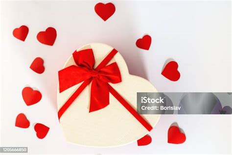 상자 빨간 리본이 달린 하트 모양의 선물 상자는 작은 빨간 골판지 하트가있는 흰색 배경에 중간에 서 있습니다 상단에서 보기입니다 발렌타인 데이와 생일 심장에 대한 스톡 사진