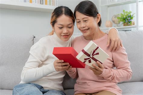 어머니의 날 귀여운 아시아 십대 소녀가 선물 상자 중년 엄마를 준다 사랑 키스 보살핌 행복한 미소는 가족 시간을 즐깁니다 특별한 날을 축하하고 생일 축하하고 새해 복 많이