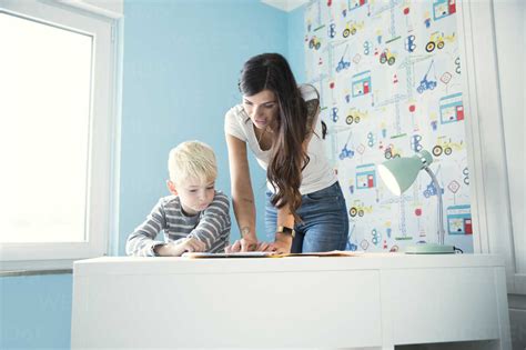 Mutter Hilft Sohn Bei Den Hausaufgaben Am Schreibtisch Lizenzfreies