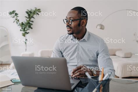 안경을 쓰고 생각에 잠긴 아프리카계 미국인 사업가가 노트북으로 작업하고 프로젝트를 숙고하고 사무실 책상에 앉아 있다 30 34세에 대한 스톡 사진 및 기타 이미지 Istock