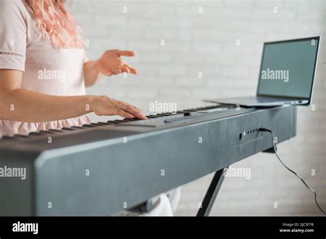 The Woman Plays The Synthesizer And Looks At The Laptop Screen Close Up Of Female Hands On The