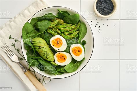 아보카도 아스파라거스 검은 참깨와 가벼운 슬레이트 돌 또는 콘크리트 배경에 접시에 시금치구를 구겨진 신선한 야채 샐러드 그릇에 균형 잡힌 점심 맨 위 보기입니다 모의 0명에