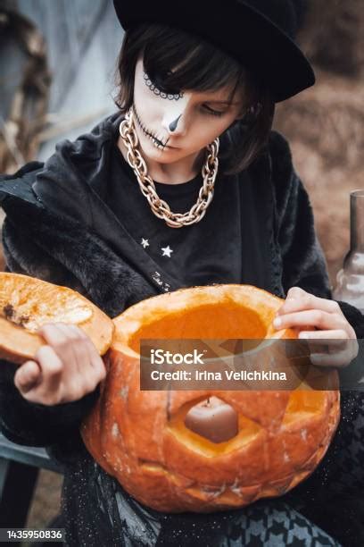 할로윈을 축하하는 아름다운 무서운 어린 소녀 무서운 블랙 화이트 하프 페이스 메이크업 마녀 의상 세련된 이미지 공포 거리의 헛간에서 어린이 파티에서 재미 모자 재킷 호박 잭