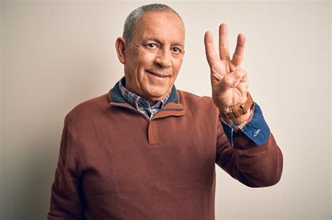 고립 된 흰색 배경 위에 서있는 우아한 스웨터를 입은 선임 잘생긴 남자는 자신감과 행복한 미소를 지으면서 손가락 번호 3을