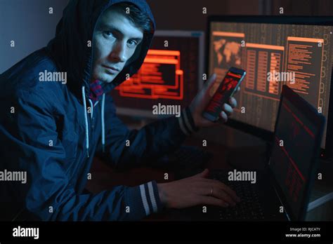 Male In The Hood Looking In The Camera Hacker Attacks And Online Fraud In The Dark On The