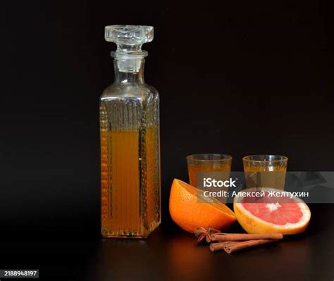 계피와 아니스를 곁들인 오렌지 자몽 리큐어 잘 익은 과일과 향신료 옆에 있는 검은색 배경의 크리스탈 그릇에 담긴 강한 수제 알코올 0명에 대한 스톡 사진 및 기타 이미지
