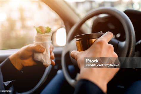 한 입 먹기 위해 멈추세요 남자는 차 안에서 간식을 먹고 커피나 차를 마십니다 음식 클로즈업 개념입니다 거리에 대한 스톡 사진