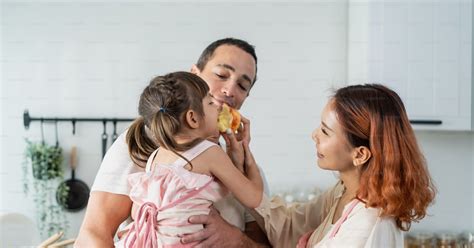 아시아의 아름다운 젊은 어머니는 부엌에서 아기 아이와 함께 음식을 요리합니다 행복한 가족은 집에서 함께 휴가를 보내고 사랑하는 부모는 어린 딸을 위해 앞치마를 묶고 아침