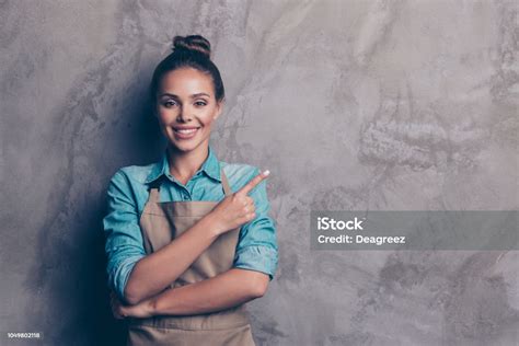 멋진 좋은 사랑 스러운 잘생긴 젊은 여자의 초상화 빈 공간 서 회색 질감된 벽 배경과 텍스트 복사 공간에 고립에서 손가락을 가리키는 웨이트리스에 대한 스톡 사진 및 기타