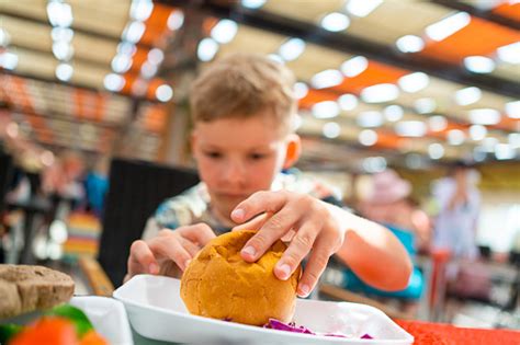 소년은 길거리 카페에서 점심을 먹고 있다 아이가 햄버거를 먹는다 어린이 메뉴 건강에 좋지 않은 음식에 대한 스톡 사진 및 기타 이미지 건강에 좋지 않은 음식 고기