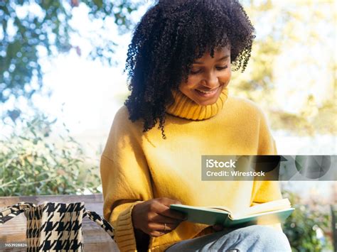 노란 스웨터를 입고 야외에서 책을 읽는 스페인의 아프리카 여성 곱슬 머리에 대한 스톡 사진 및 기타 이미지 곱슬 머리 노랑 사람 얼굴 Istock