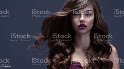 긴 갈색 곱슬 머리를 가진 아름다운 여자의 얼굴 물결 모양의 헤어 스타일 패션 모델 스튜디오에서 포즈를 취하는 곱슬 머리를 가진 매력적인 어린 소녀 보라색 메이크업 여성