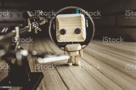 나무 로봇 안드로이드는 돋보기 아래 테이블에 서있다 돋보기가 있는 금속 클램프 아름답게 유리에 로봇의 얼굴 인간 연구 개념 눈