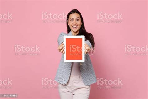 분홍색 파스텔 배경에 고립 된 빈 빈 화면으로 태블릿 Pc 컴퓨터를 들고 줄무늬 재킷에 쾌활 한 젊은 여자의 초상화 사람들은