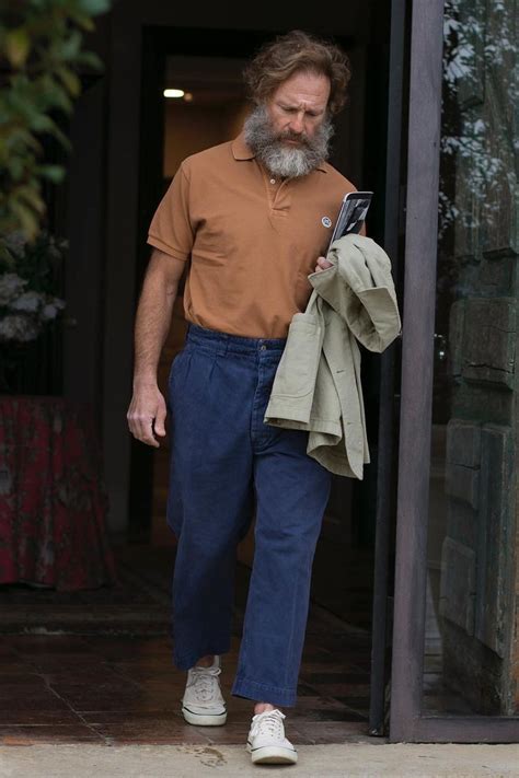 Man Wearing Blue Pleated Pants Tucked In Brown Polo Shirt And Khaki