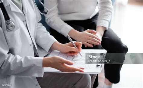 의사와 환자는 클리닉 사무실의 소파에 앉아 있습니다 초점은 약물 기록 기록 양식을 작성하는 여성 의사의 손에 있습니다 의학 개념 건강 진단에 대한 스톡 사진 및 기타 이미지