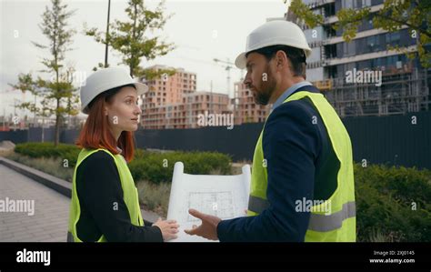 Two Contractors Civil Engineers Checking Information In Blueprint