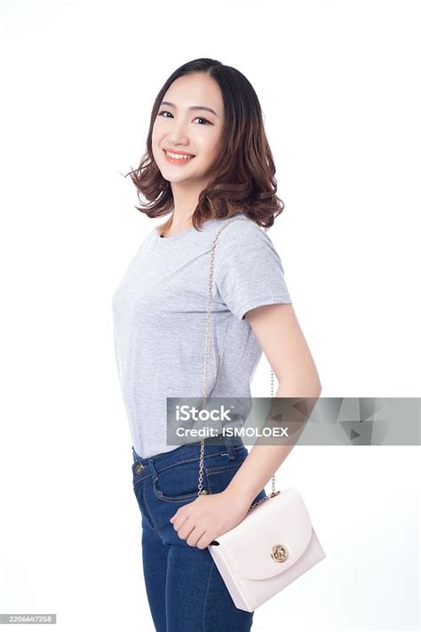 분홍색 핸드백을 든 젊은 여성이 서서 미소를 짓고 있습니다 T 셔츠에 대한 스톡 사진 및 기타 이미지 T 셔츠 가방 개인