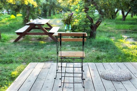 테이블과 의자가있는 빈 카페 나무 테라스 카페 레스토랑의 거리 외관 테이블 위의 꽃병에 꽃 피크닉 또는 자연의 레저를위한 여름 정원의 가구 아늑한 실내 안뜰 과수원에 대한