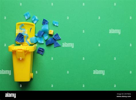 Mini Recycling Bin And Broken Plastic Pieces On Green Background Flat