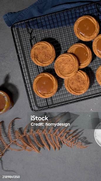 어두운 표면에 캐러멜 소스 한 병 소금 한 그릇 말린 고사리 잎과 함께 냉각 랙에 올려 소박한 미학을 연출합니다 Comfort Food에 대한 스톡 사진 및 기타 이미지