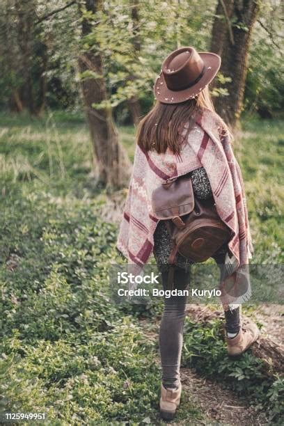 저녁 햇살에 숲에서 걷는 배낭 모자에 세련 된 Hipster 소녀 여자 여행자 다시 햇빛이 나무 들 사이 볼 텍스트를 위한 공간입니다 방 랑 벽입니다 대기 순간 걷기에 대한