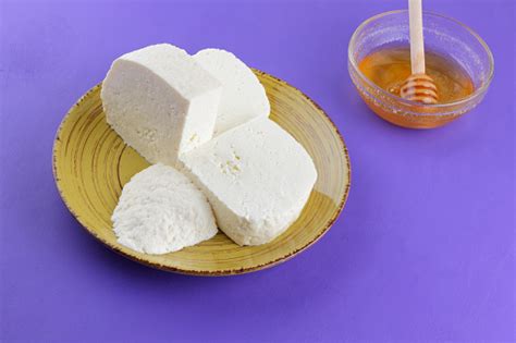 치즈와 꿀 보라색 배경에 노란색 접시 미니 멀 스타일 복사 공간 평면도 우유 아침 나무 칼 붙이 자외선 낙농 제품에 Feta 치즈를 그리스 꿀 건강한 식생활에 대한 스톡