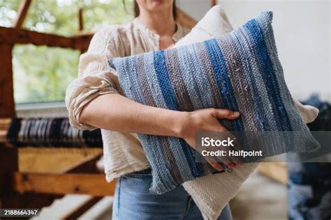 나무 베틀 옆의 젊은 사업가 재활용 직물로 만든 짠 덮개가 있는 베개를 들고 있습니다 비즈니스와 순환 경제의 업사이클링 고급에 대한 스톡 사진 및 기타 이미지 Istock