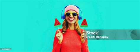 푸른 배경에 과일 육즙 롤리팝 또는 아이스크림 모양의 수박 조각으로 음악을 듣고 헤드폰에 행복 웃고 젊은 여성의 여름 신선한 다채로운 초상화 20 29세에 대한 스톡 사진