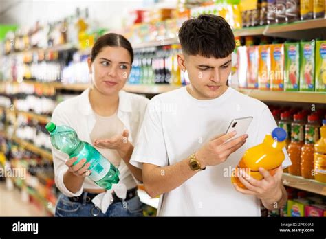 Couple Scanning Barcodes On Bottles Of Beverages With Phone In Supermarket Stock Photo Alamy