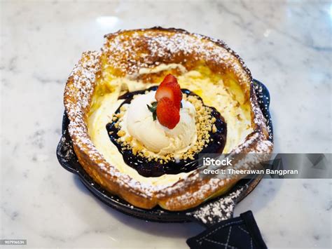 에 입힌 분말 초콜릿 소스 무너질 신선한 딸기를 얹은 바닐라 아이스크림 맛 있는 아름 다운 네덜란드 아기 팬케이크 주철 프라이팬