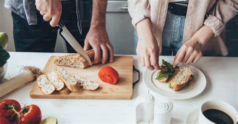 부엌에서 빵과 야채를 썰면서 함께 샌드위치를 준비하는 백인 커플 사진 Unsplash의 빵 이미지