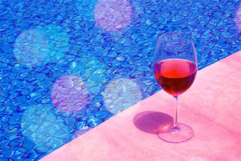 Crystal Glass With Red Wine On The Edge Of A Swimming Pool During A