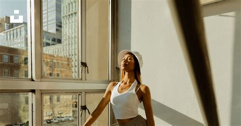 갈색 탱크 탑과 회색 바지를 입은 여자가 흰색 콘크리트 계단에 앉아 있다 사진 Unsplash의 무료 유행 이미지