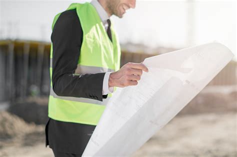 프로젝트와 하드 모자를 가진 젊은 건설 엔지니어 남자의 측면보기 건물 외관에 대한 스톡 사진 및 기타 이미지 건물 외관 건설 산업 건설 현장 Istock