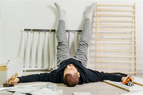집에서 바닥에 누워 있는 한 남자가 Diy 가구를 파괴하고 필사적으로 피곤하게 만들려고 셀프 조립 프로젝트 중에 지쳤습니다 35 39세에 대한 스톡 사진 및 기타 이미지