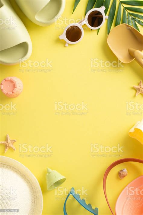 아이들과 함께하는 열대 리조트 야자수 잎과 조개껍데기 모래 장난감 카피스페이스가 있는 노란색 고립된 배경에 파나마가 있는 슬리퍼로 둘러싸인 빈 장소의 상단 수직 보기 사진
