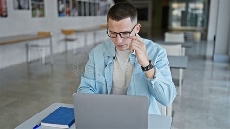 Young Man Removing Glasses And Stretching In A Modern Library With