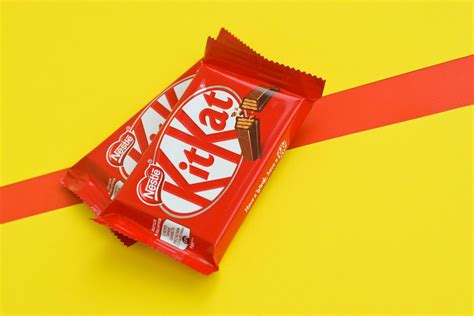 Kit Kat Chocolate Bars In Red Wrapping Lies On Yellow And Red