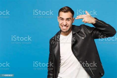 검은 색 자 켓 흰색 T셔츠에 젊은 슬픈 면도 남자가 그가 파란색 벽 배경에 고립 촬영에 대 한 것 처럼 머리를 포인트 손가락을 찾고 사람들 라이프 스타일 개념입니다 복사