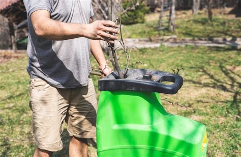 Premium Photo Man Putting Tree Branches Into Garden Shredder