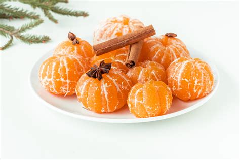 흰색으로 분리된 흰색 접시에 스타 아니스 향신료와 계피 스틱으로 장식된 껍질을 벗긴 육즙이 많은 감귤의 매크로 샷 겨울 휴가 분위기 메리 크리스마스와 새해 복 많이 받으세요