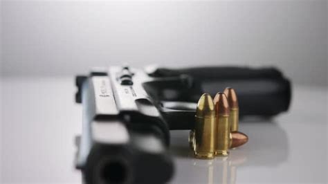 Gun Control 9mm Handgun With Bullets Rotating On A Reflective Surface