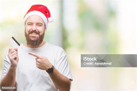 손과 손가락으로 가리키는 매우 행복 격리 된 배경 위에 신용 카드를 들고 크리스마스 모자를 쓰고 젊은 백인 남자 가리키기에 대한 스톡 사진 및 기타 이미지 Istock