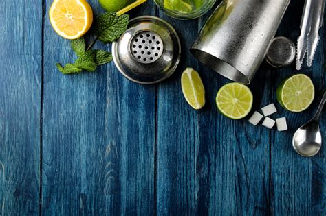 라임 민트 레몬이 들어간 유리 잔에 담긴 모히토 칵테일과 파란색 나무 테이블에 바 액세서리가 있습니다 모히토를 만드십시오 평면도 0명에 대한 스톡 사진 및 기타 이미지