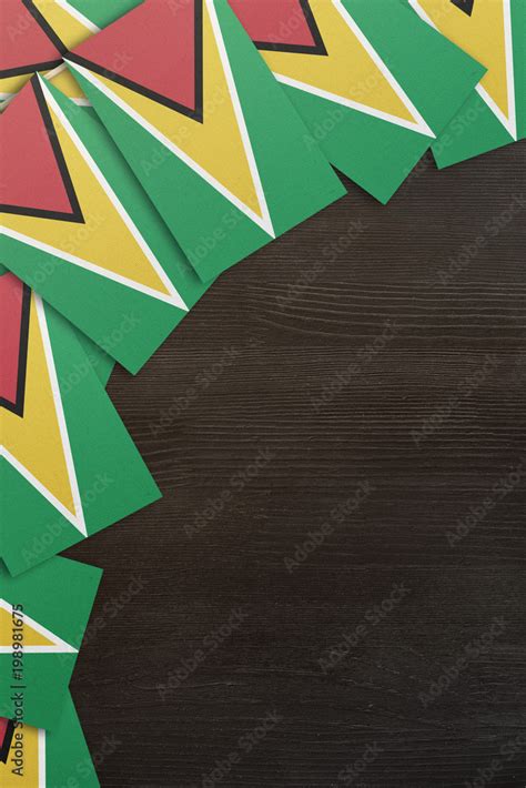 Guyana Small Flags Framing A Wood Texture Background With Copy Space