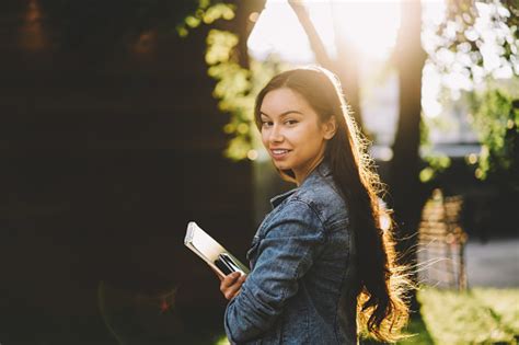 매력적인 웃는 Hipster 여자의 반 길이 초상화도 손에 카메라를 보고 서 쾌활 한 학생 야외 서 하는 동안 노트북을 들고 데님 자 켓 입고 공간 영역 복사 갈색 머리에