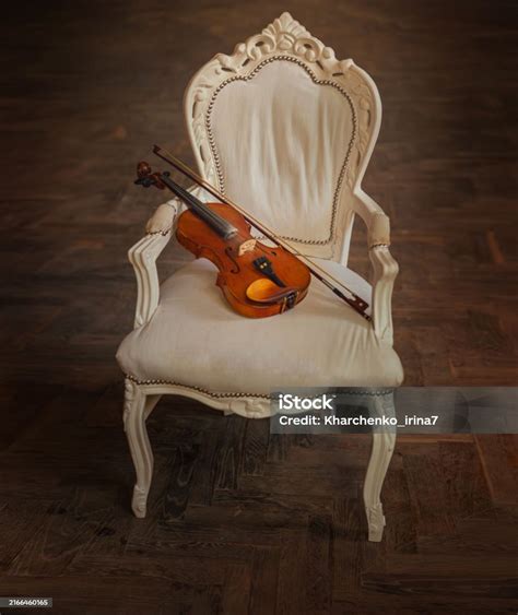 나무 바이올린은 안락 의자 오래 된 빈티지 스타일 클래식 가구 로얄 왕좌 의자 흰색 패브릭 실내 장식 어두운 고딕 양식 판타지 룸 배경에 놓여 있습니다 사람이 촬영하지 않는