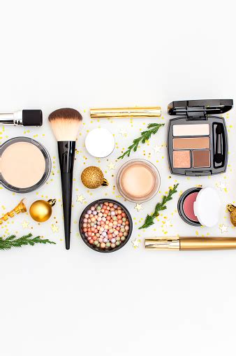 메이크업 마스카라 파운데이션 크림 립스틱 아이섀도우 홍당무 볼과 새해 장식 골드 크리스마스 볼 색종이 별 전나무 가지 밝은 배경에 플랫 누워 상단 뷰 화장품 휴일 크리스마스
