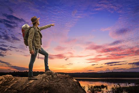 산 강변의 상단에 남자 하이킹과 배낭 배낭을 가진 여행자 젊은 남자는 일몰 여행 개념에 절벽에 앉아 20 24세에 대한 스톡